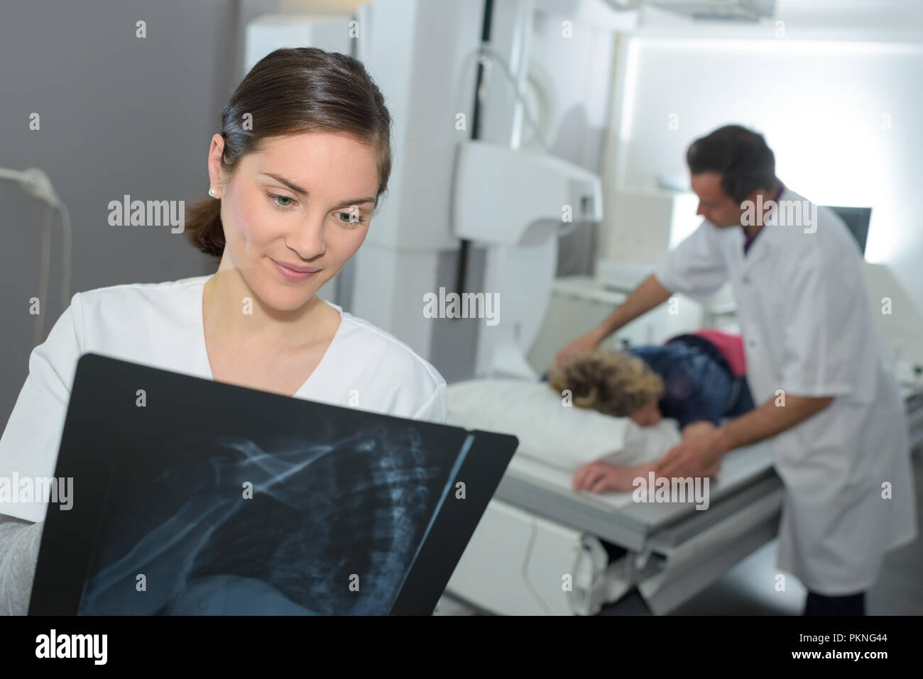 female doctor looking at x-ray with patient and assistant behind Stock ...