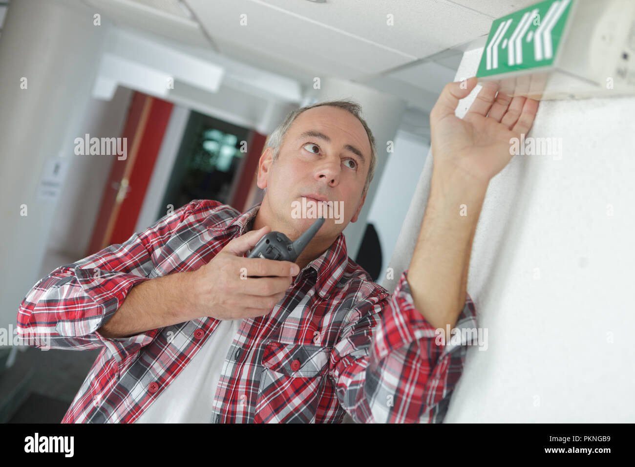 technician fitting an emergency sign Stock Photo - Alamy