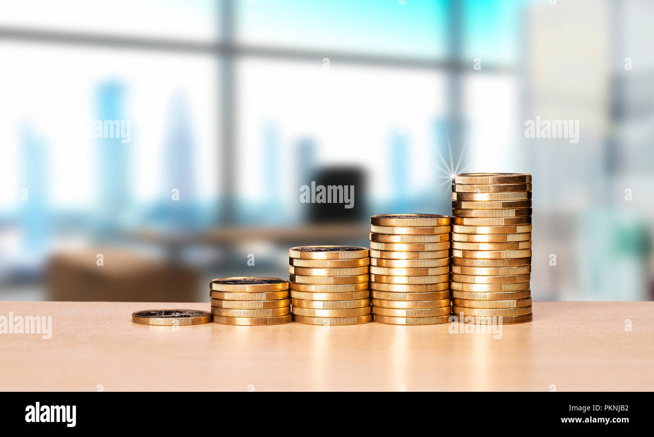 Rising stacks of coins on the desk in an office with a skyline in the ...