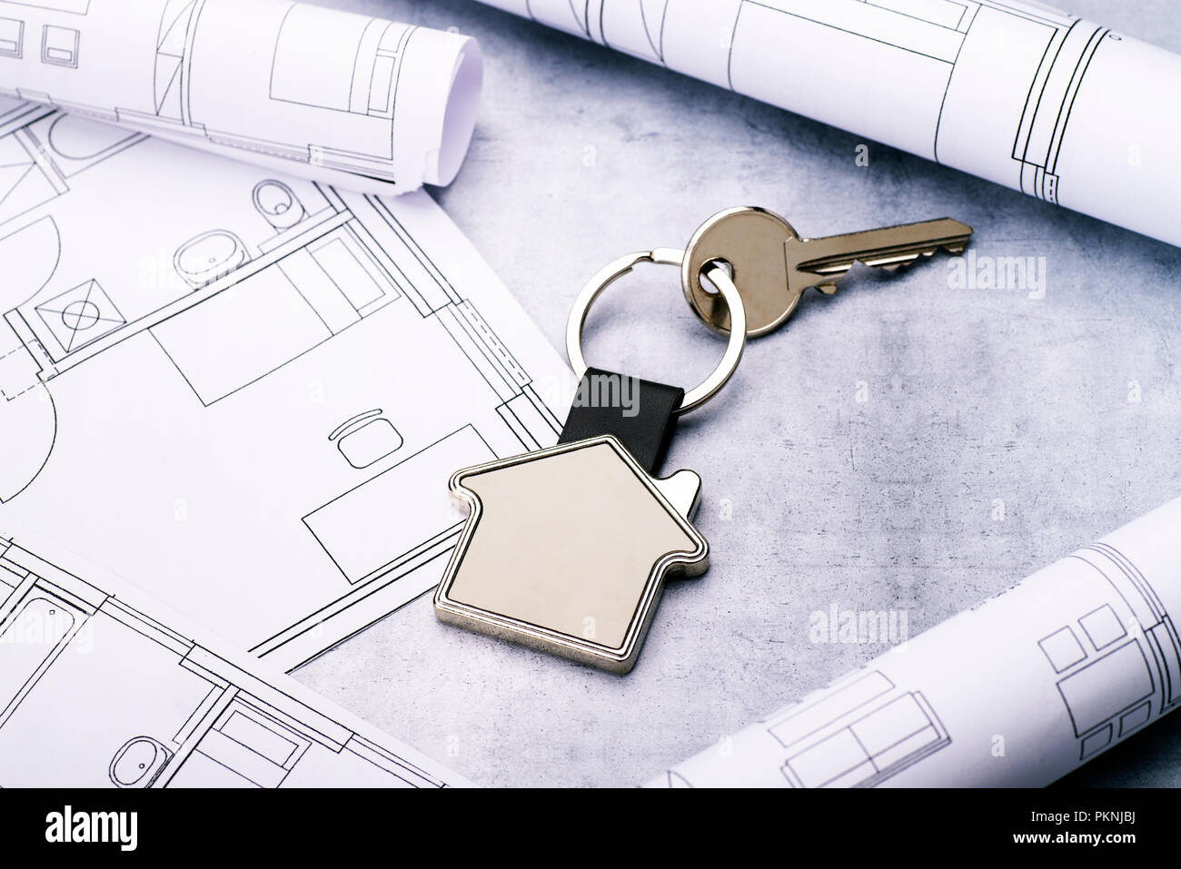 Key with house as key fob and blueprints on a concrete background Stock ...