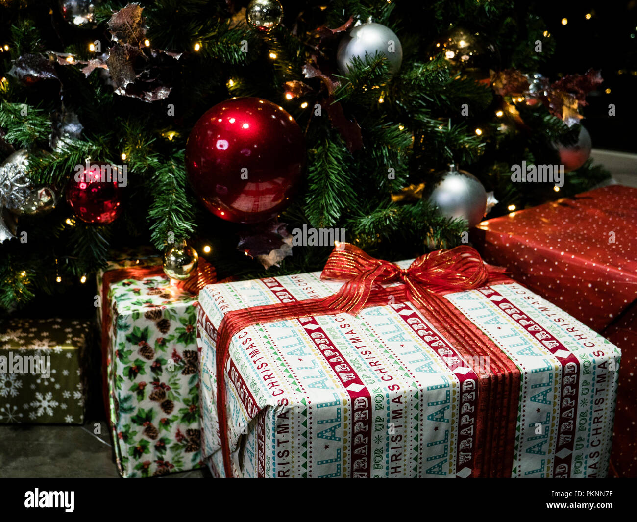 Christmas presents by indoor Christmas tree Stock Photo - Alamy