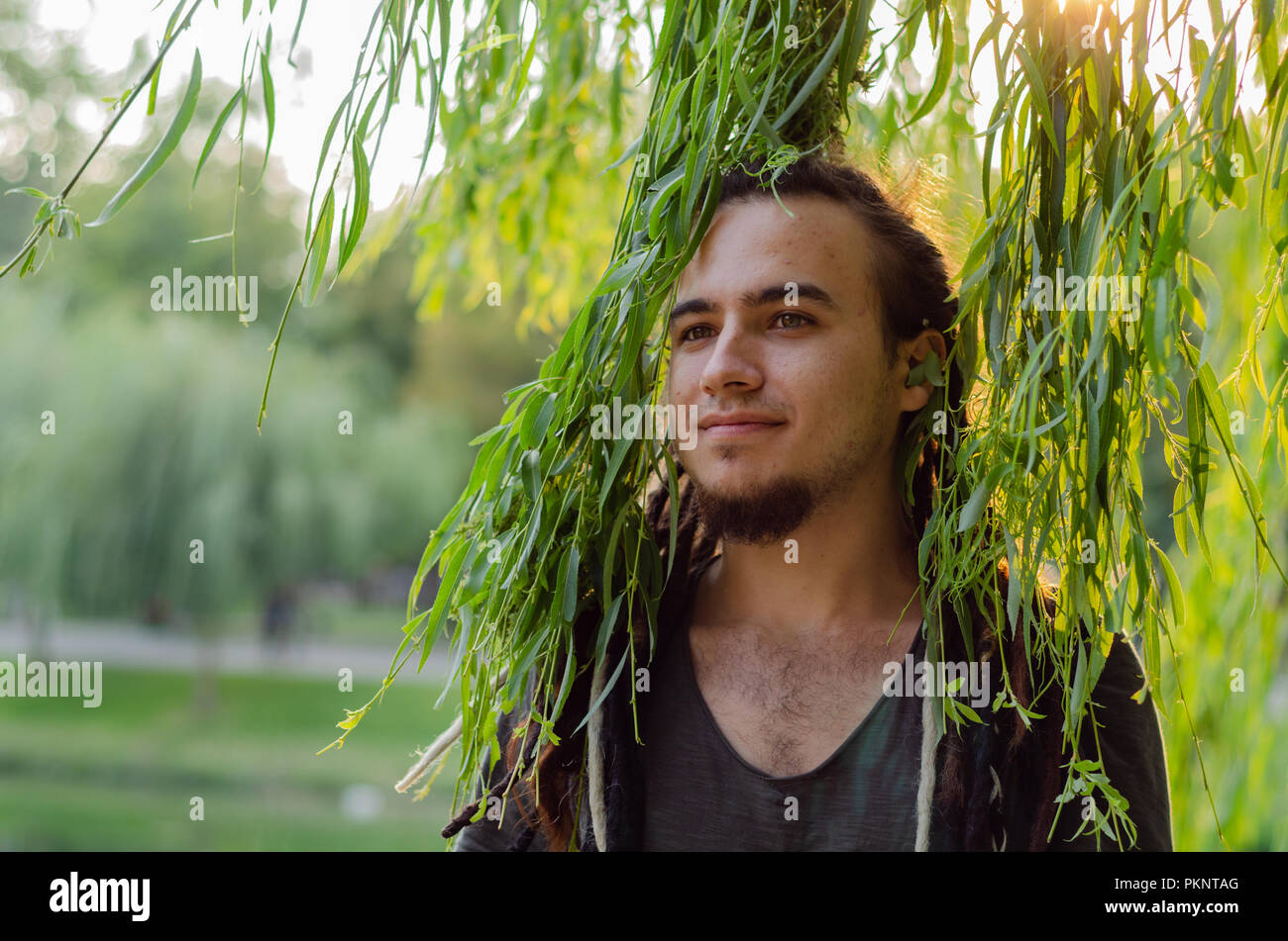 The man with the beard and the long hair is looking through the leaves ...