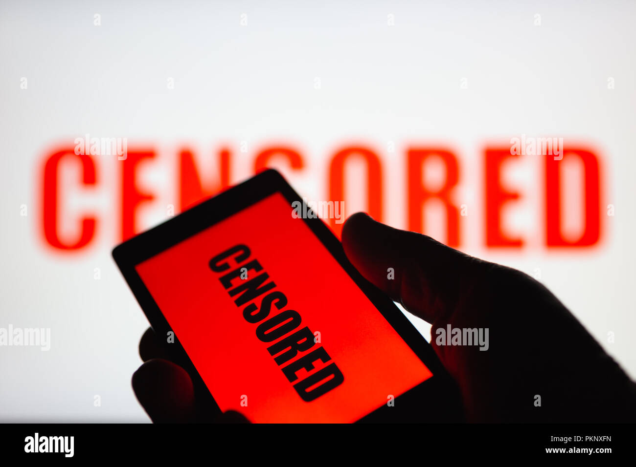 A smartphone in hand displaying the "censored" text. Same text in red ...