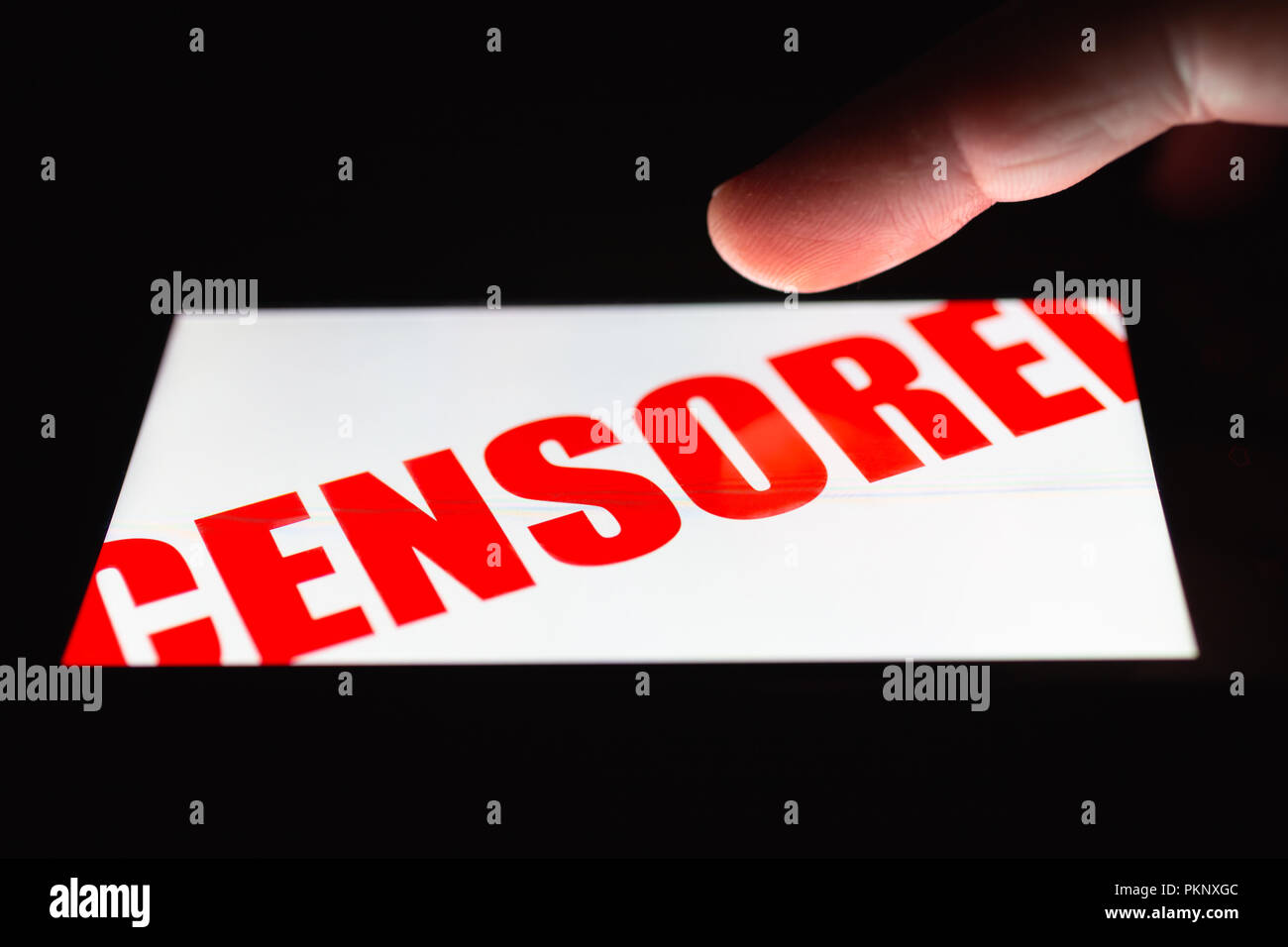 A smartphone lying on a table in the dark, displaying "censored" text ...