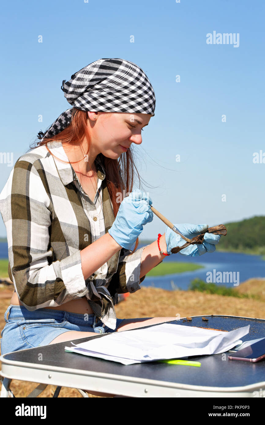 Girl archaeologist carefully cleans the find - part of the spine of a ...