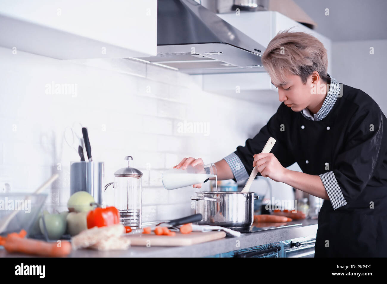 Asian cook in the kitchen prepares food in a cook suit Stock Photo - Alamy