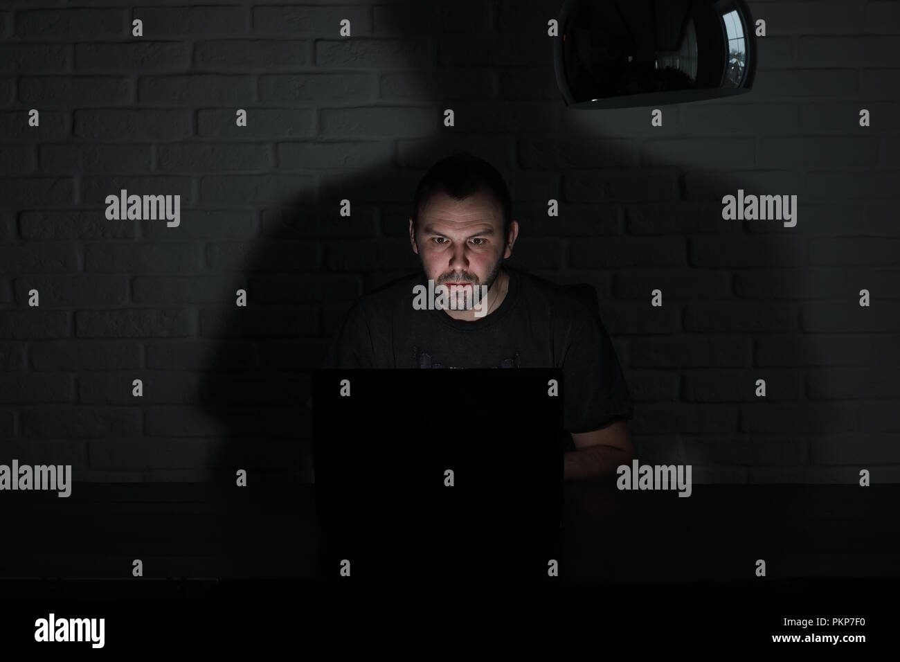 Hacker in black mask and hood at the table Stock Photo - Alamy