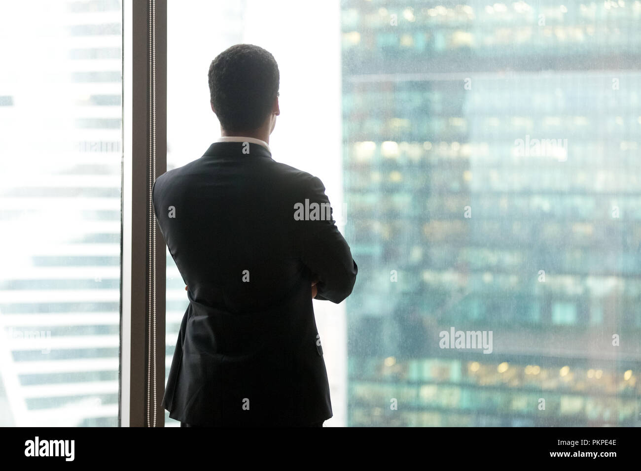 Successful thoughtful businessman looking through the window at Stock ...