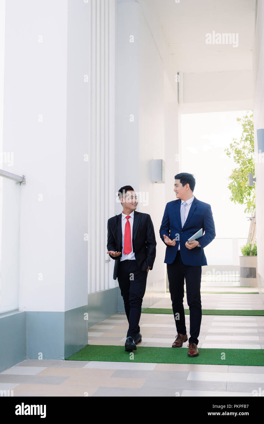 Two Vietnamese male coworkers talking and smiling Stock Photo - Alamy