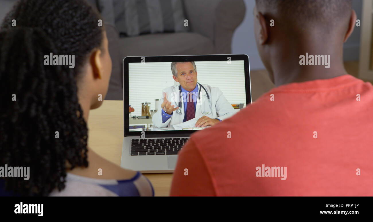 Medical doctor explaining issues to young black couple over web chat ...