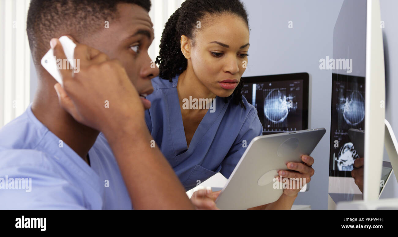 Two African American doctors using tablet and phone to work together ...