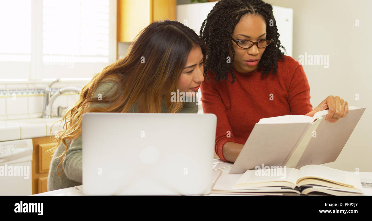 Two women students studying in kitchen with laptop computer Stock Photo ...