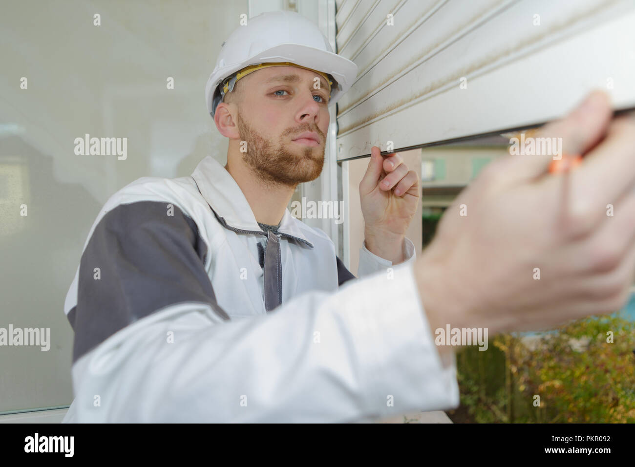 worker installing rolling shutter Stock Photo - Alamy