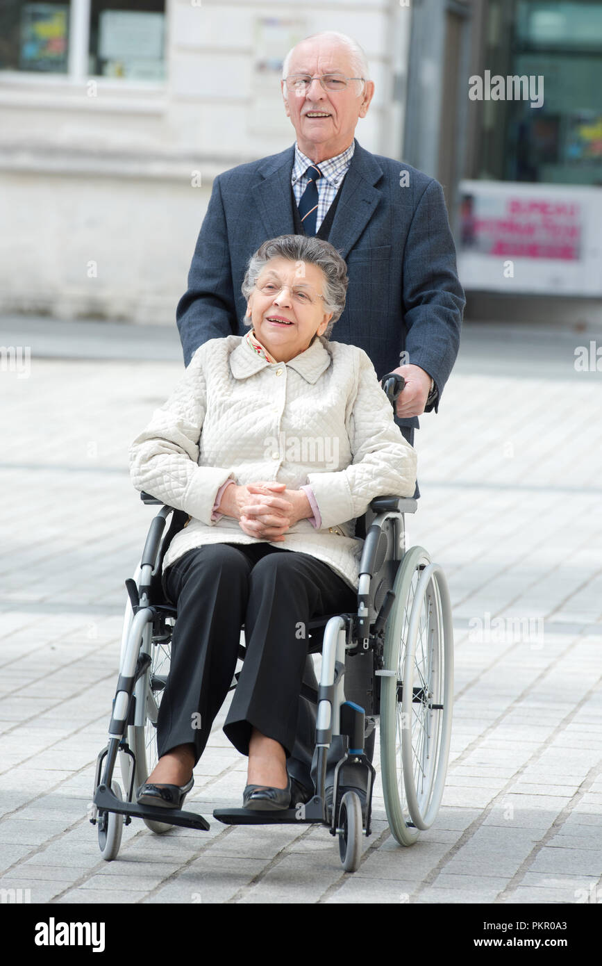 senior man pushing woman in wheelchair Stock Photo - Alamy