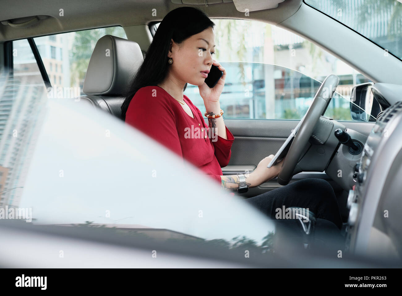 Efficient Chinese female manager working in car. Successful Asian ...