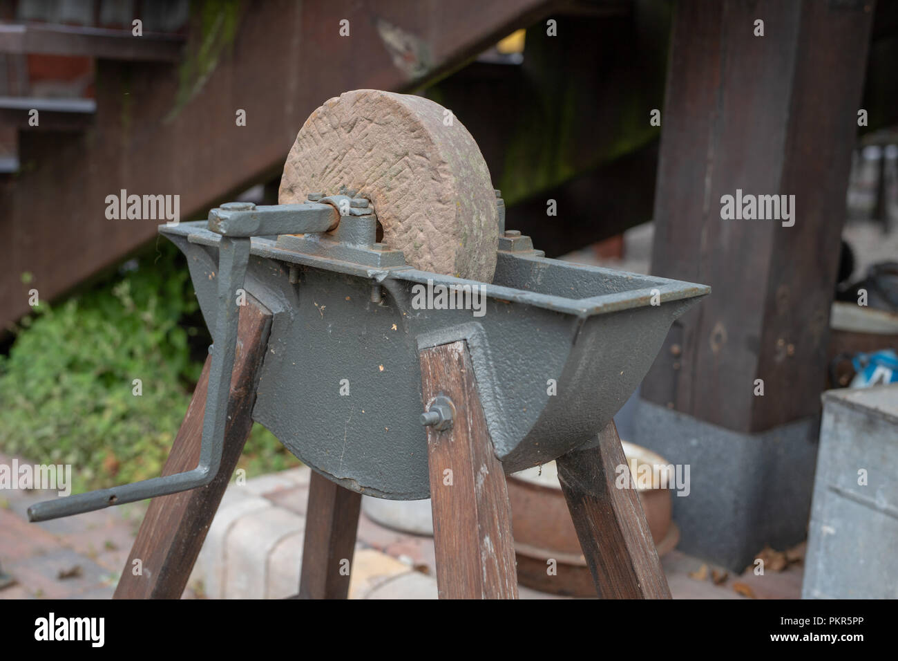 An old whetstone for sharpening knives. Grinding wheel on an old tripod ...