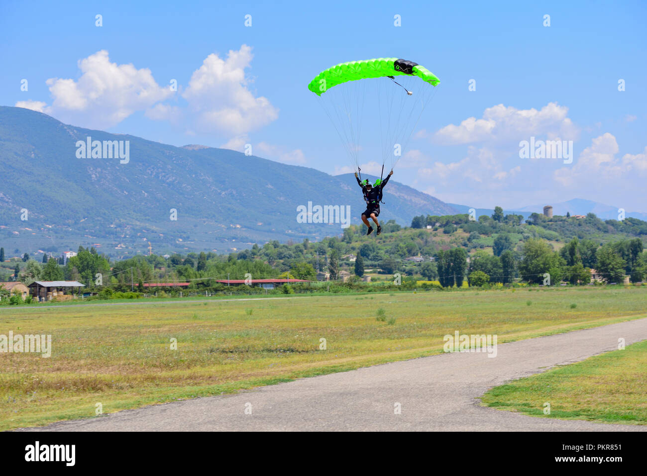 paratrooper with green parachute prepares for landing. On background ...