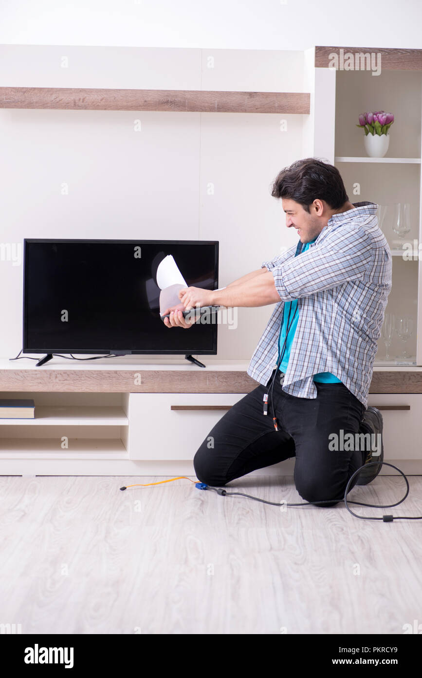 Man trying to fix broken tv Stock Photo - Alamy