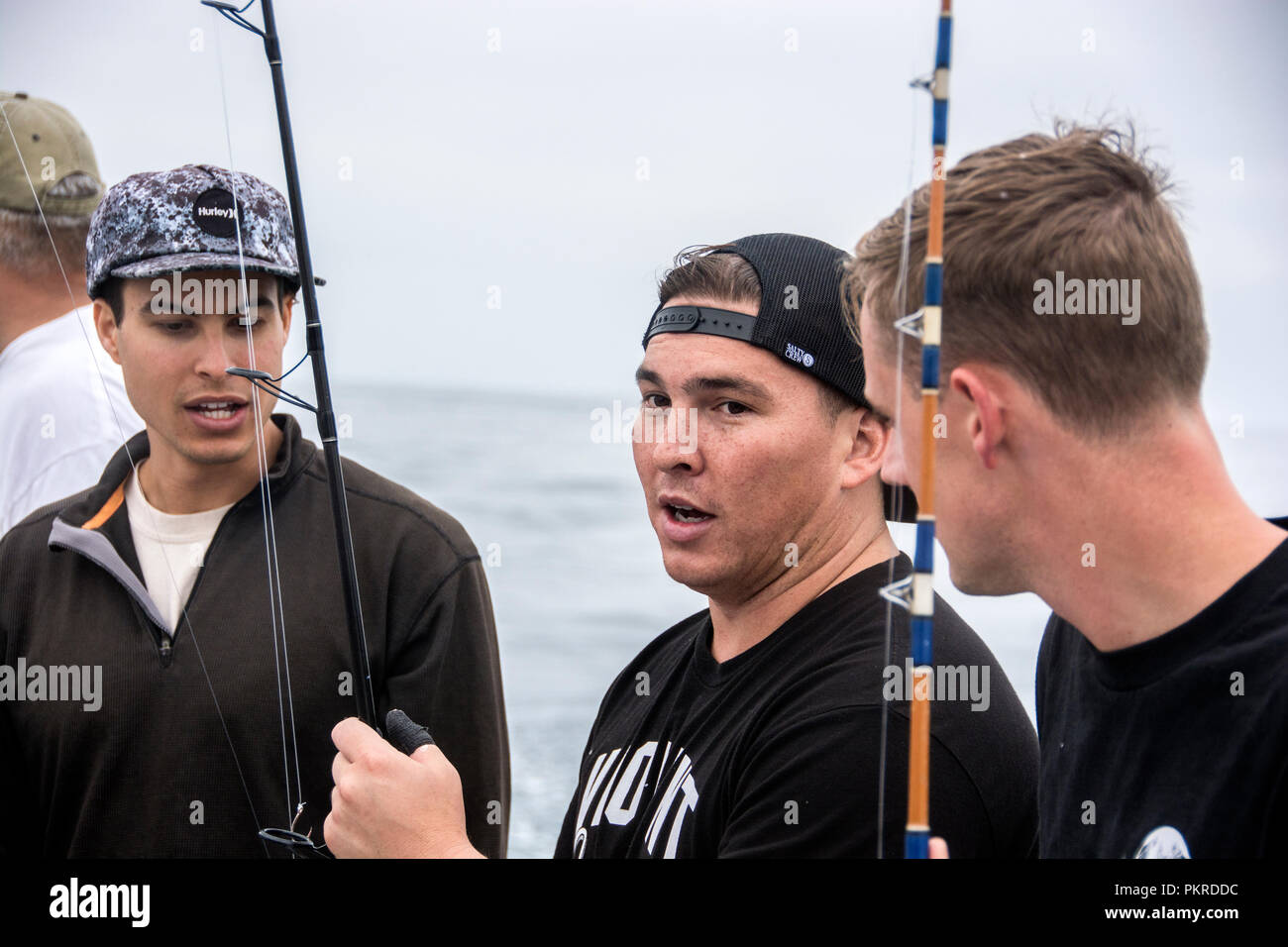 Three friends in their 20s standing around with fishing poles Stock ...