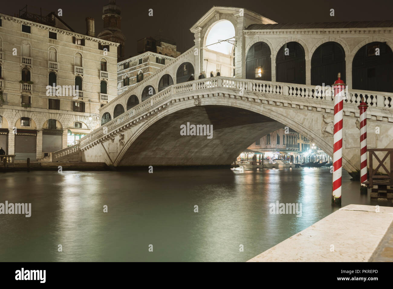 famous Rialto bridge illuminated by night above waters of Grand Canal ...