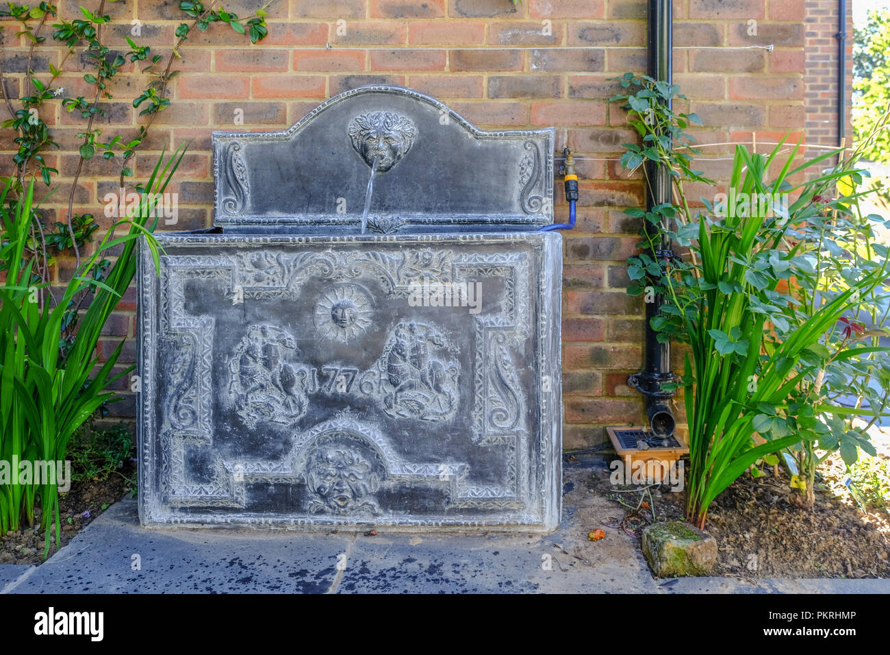 Tank water feature with flowing water standing beside a brick wall on a ...