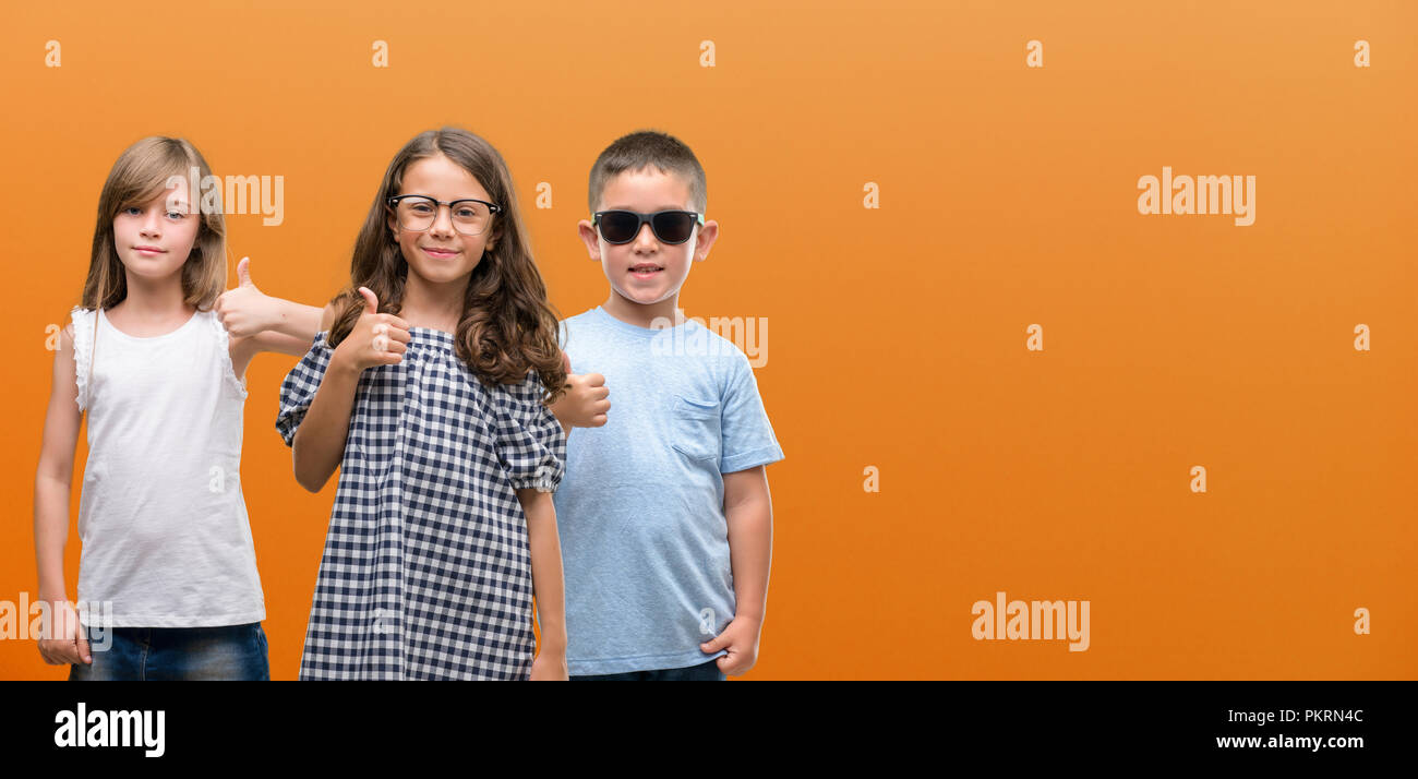 Group of boy and girls kids over orange background happy with big smile ...