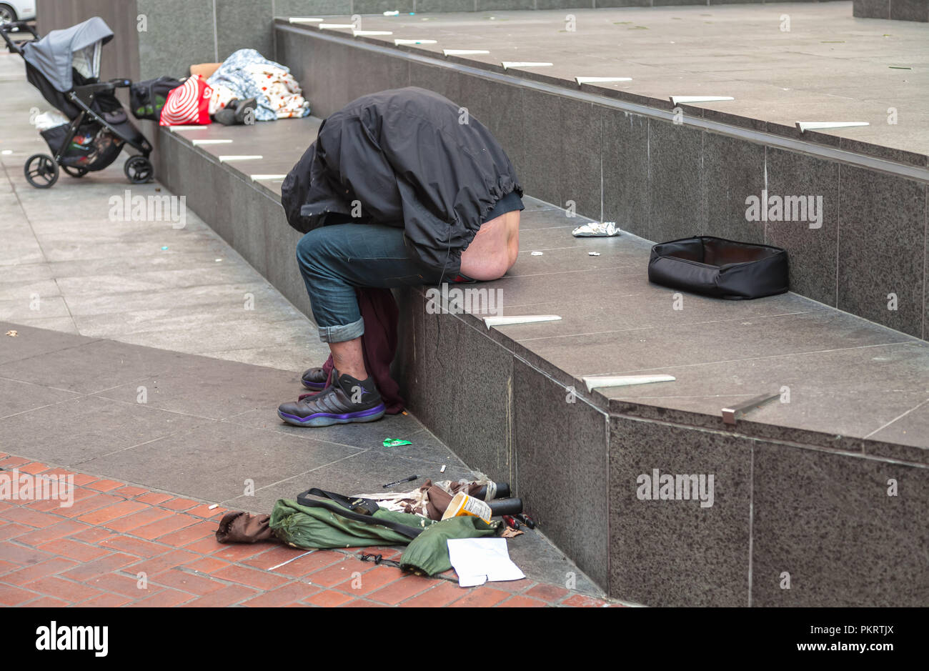 A homeless man sleeps on the street curb in San Francisco, California ...