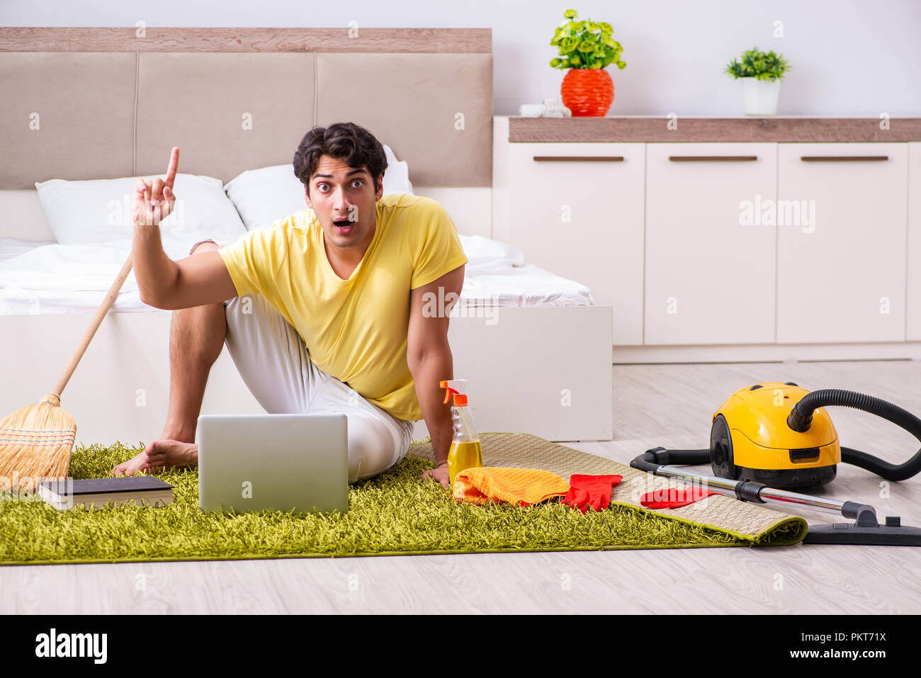 Young handsome man cleaning the bedroom and sitting at the computer ...