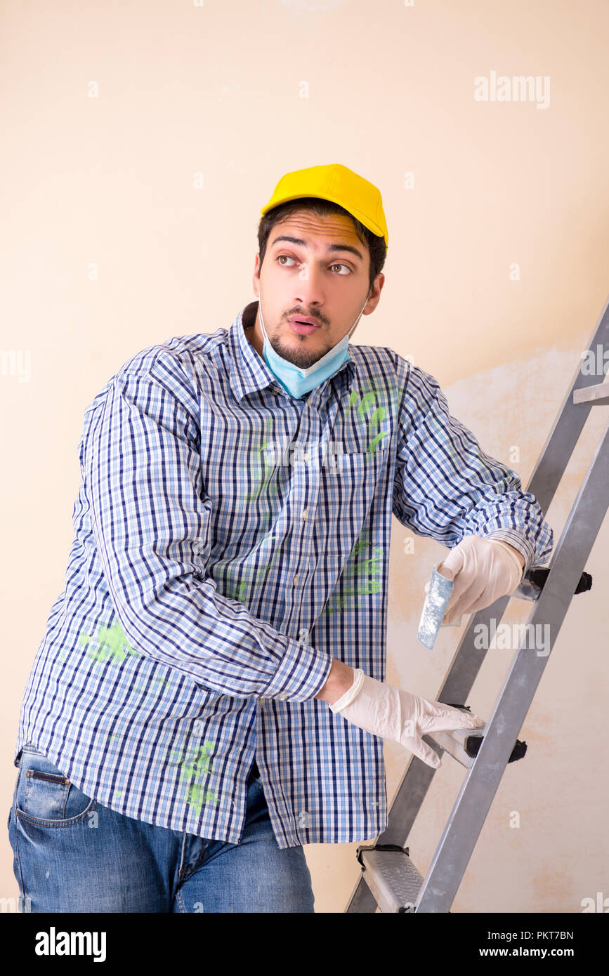 Young contractor sanding wall down with sandpaper Stock Photo - Alamy