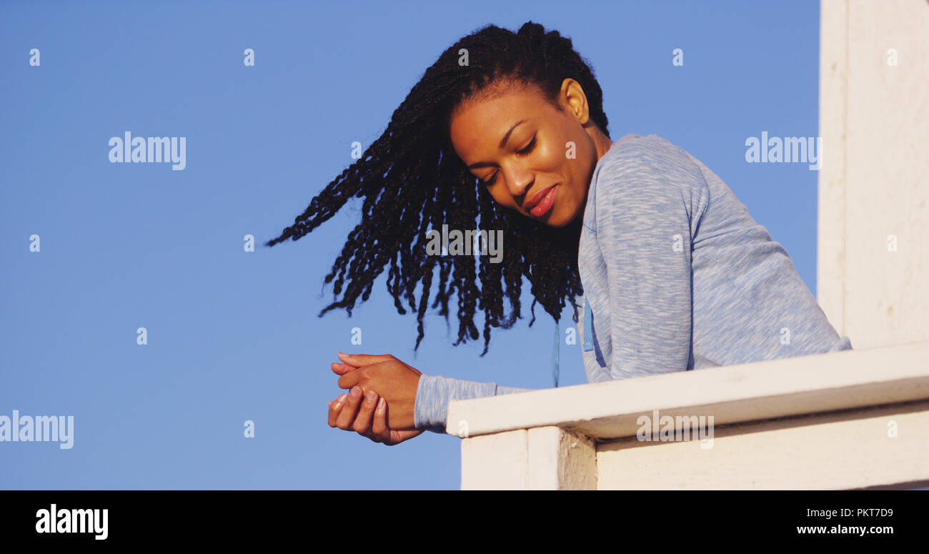 Happy black woman leaning on rail smiling Stock Photo - Alamy