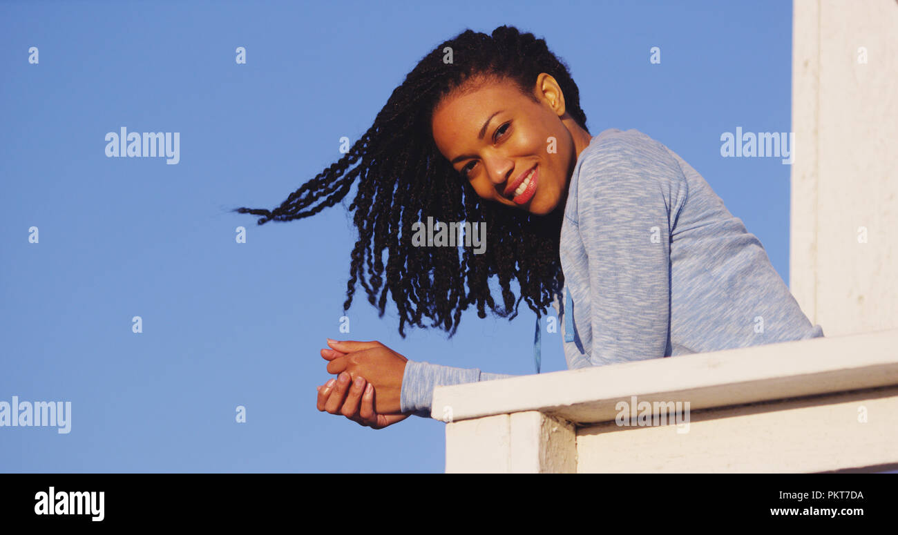 Happy black woman leaning on rail smiling Stock Photo - Alamy