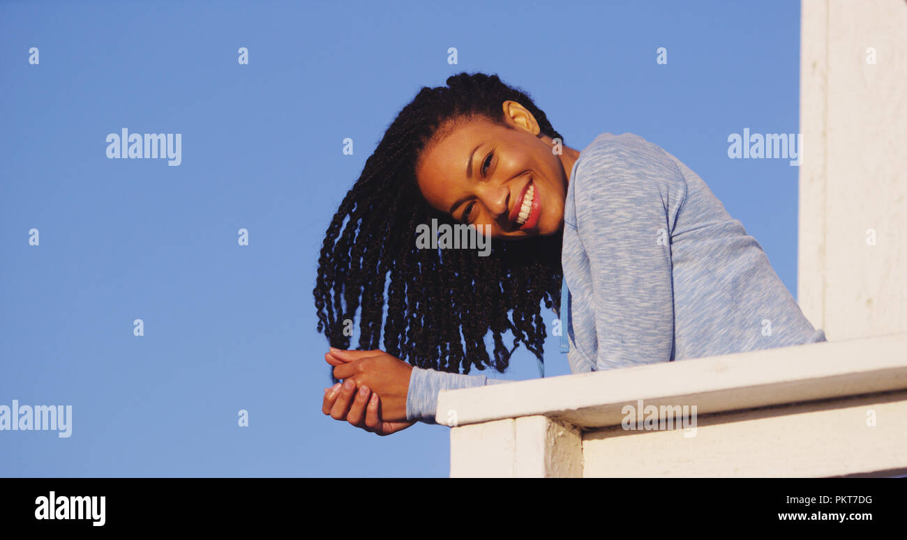 Happy black woman leaning on rail smiling Stock Photo - Alamy