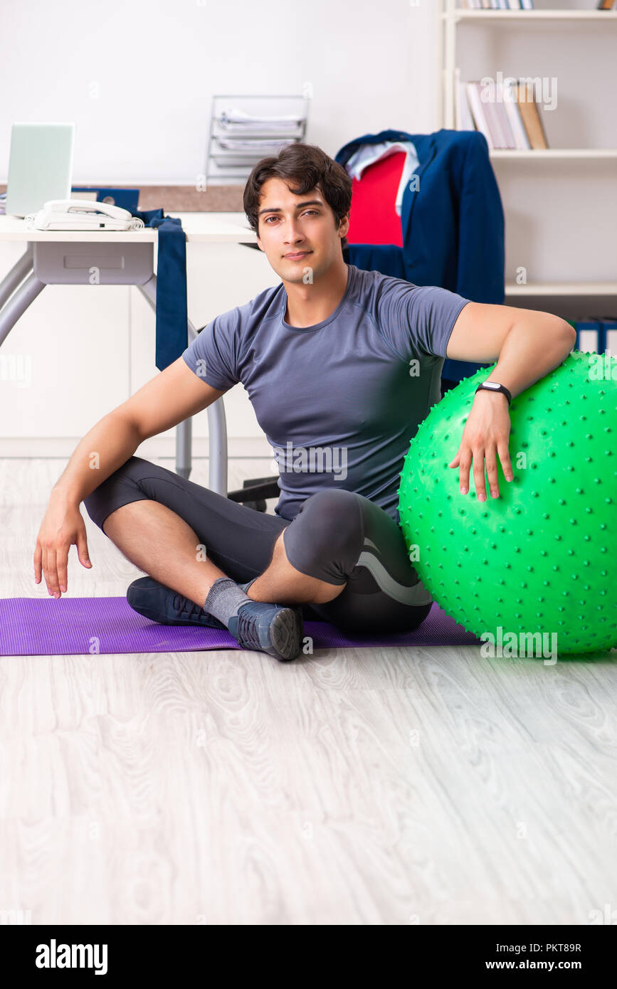 Young male employee exercising in the office Stock Photo - Alamy