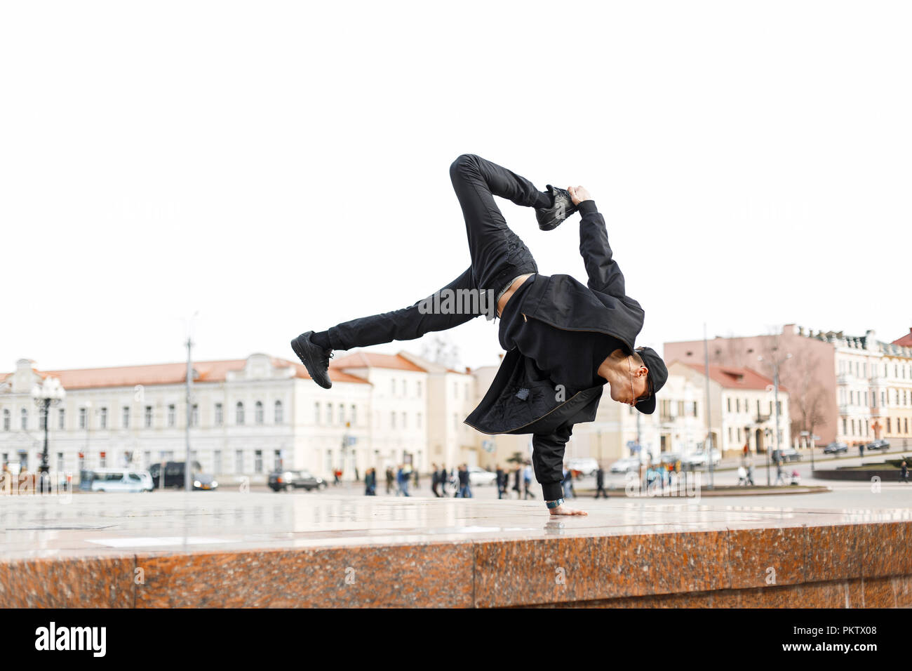 Stylish male dancer in black glasses and a cap dances on the street ...