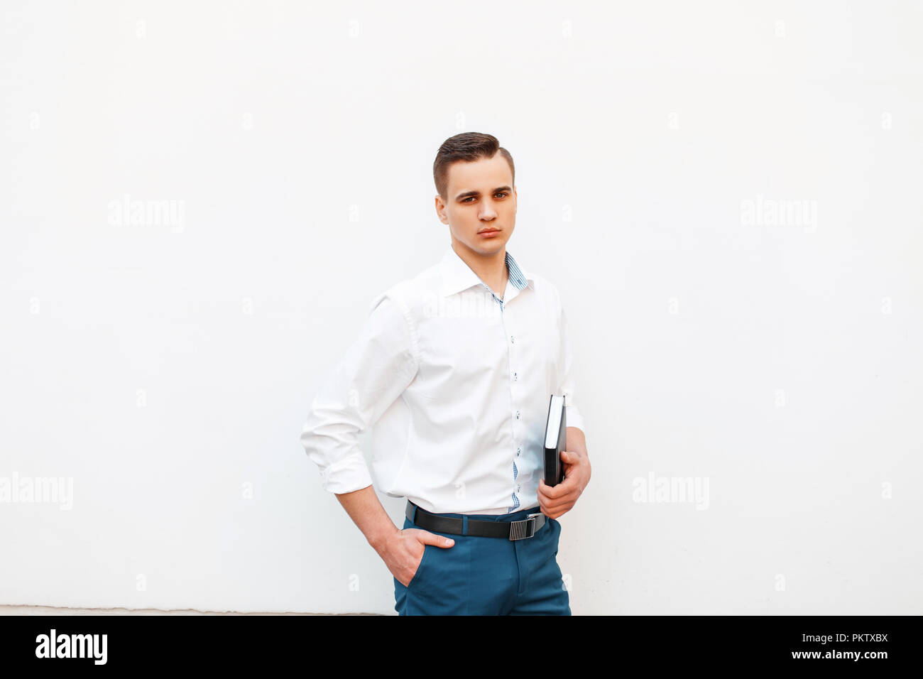 Stylish handsome man with a haircut in a white shirt holding notebook ...