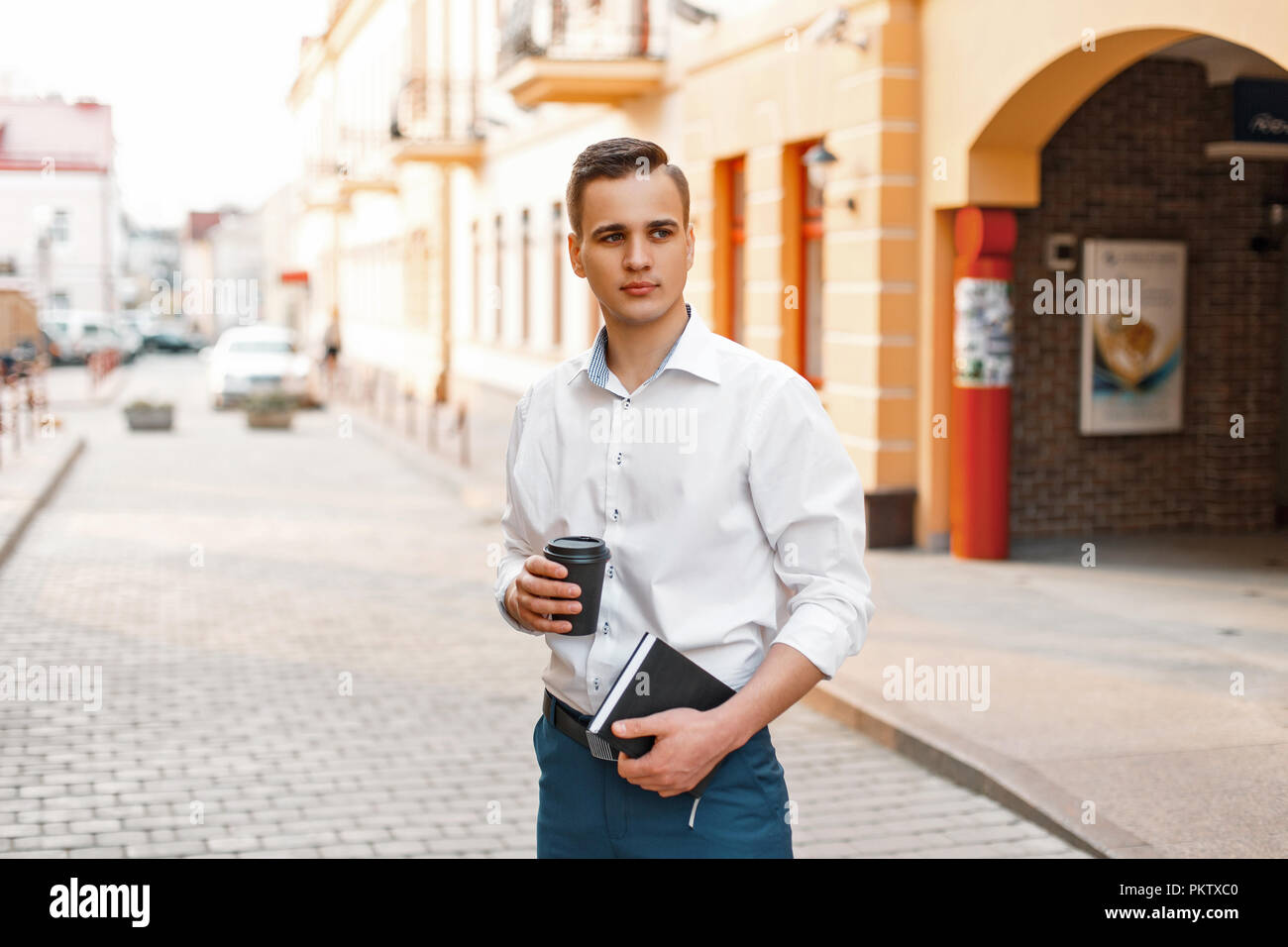 Young handsome guy with coffee and a notebook walks in the city Stock ...