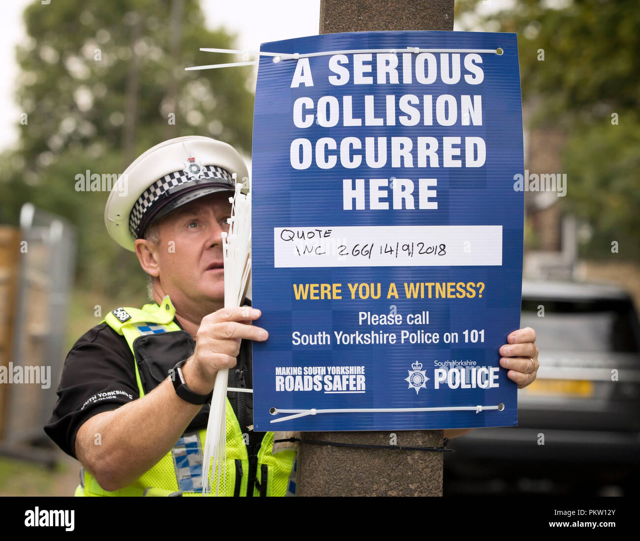 A police officer puts up a poster appealing for witnesses at the scene ...