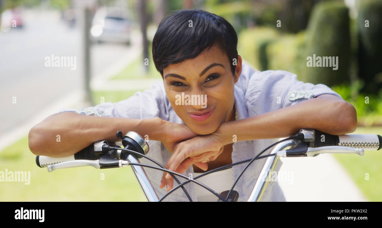 African woman smiling and leaning on bicycle handlebars Stock Photo - Alamy