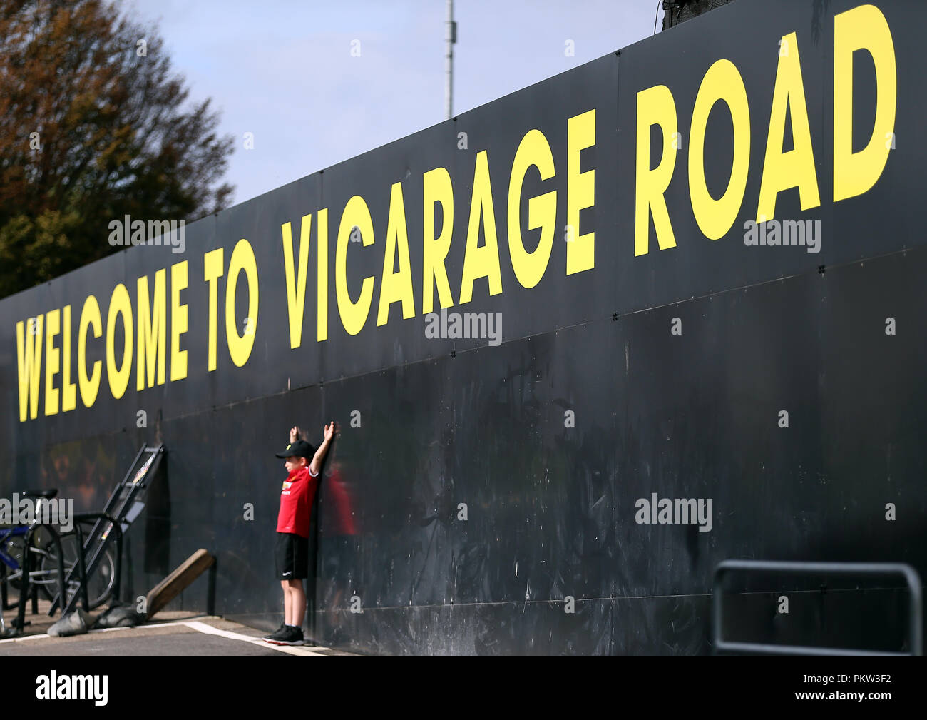 A Manchester United fan poses in front of a Welcome to Vicarage Road ...