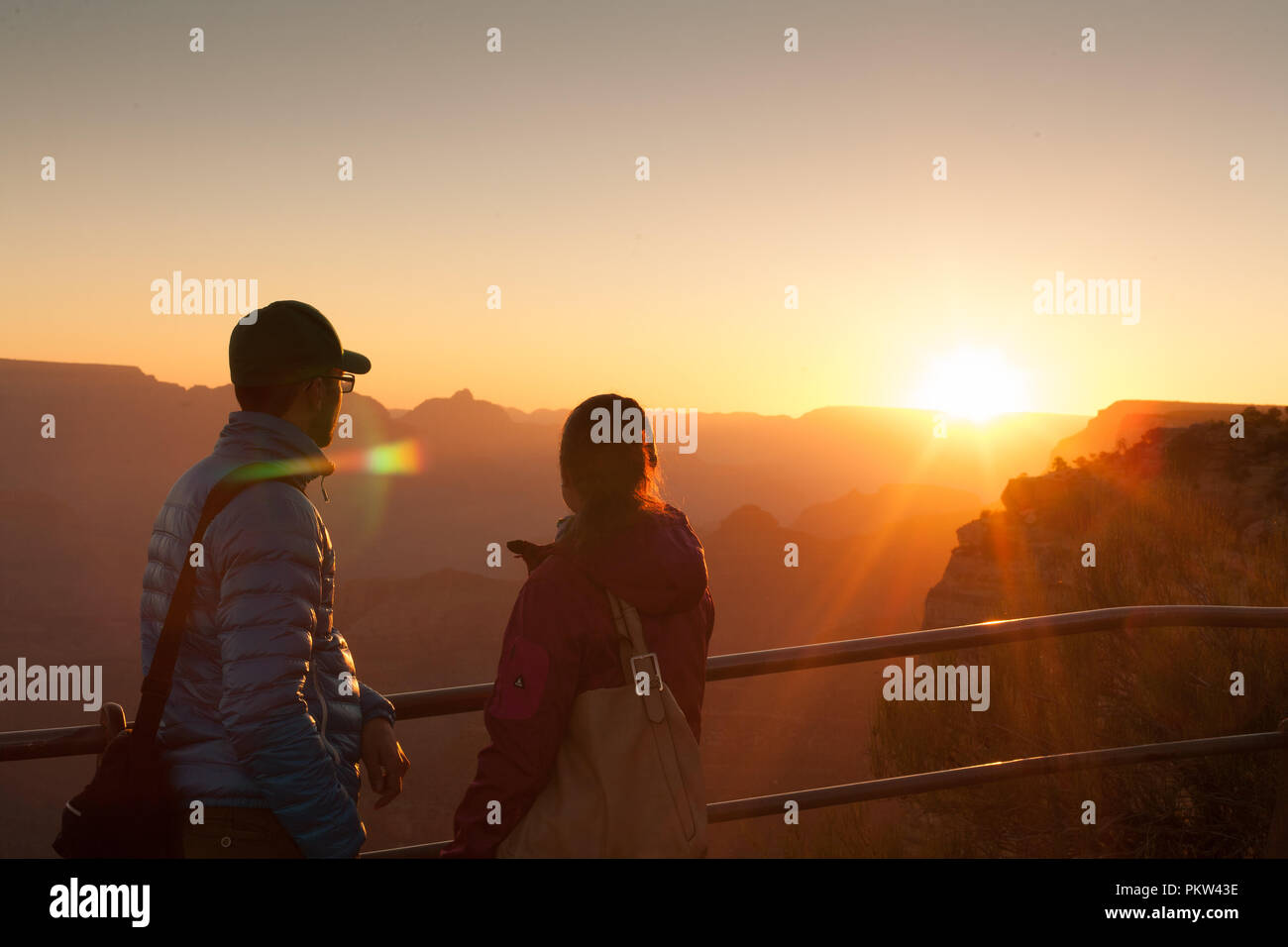 Couple of People looking towards sunrise at grand canyon south rim with ...