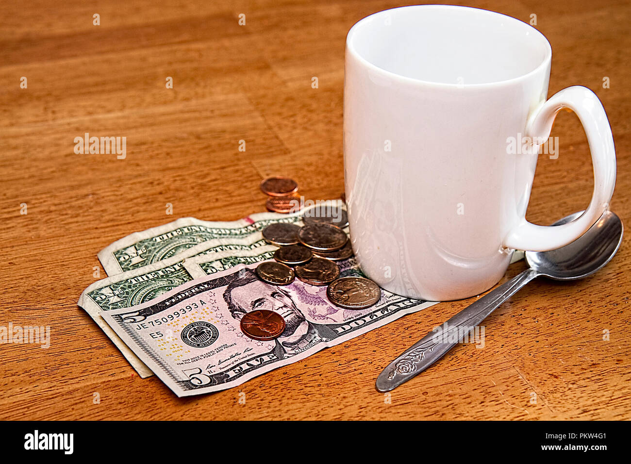 Coffee mug with spoon next to it and a tip for the dinner beneath it ...