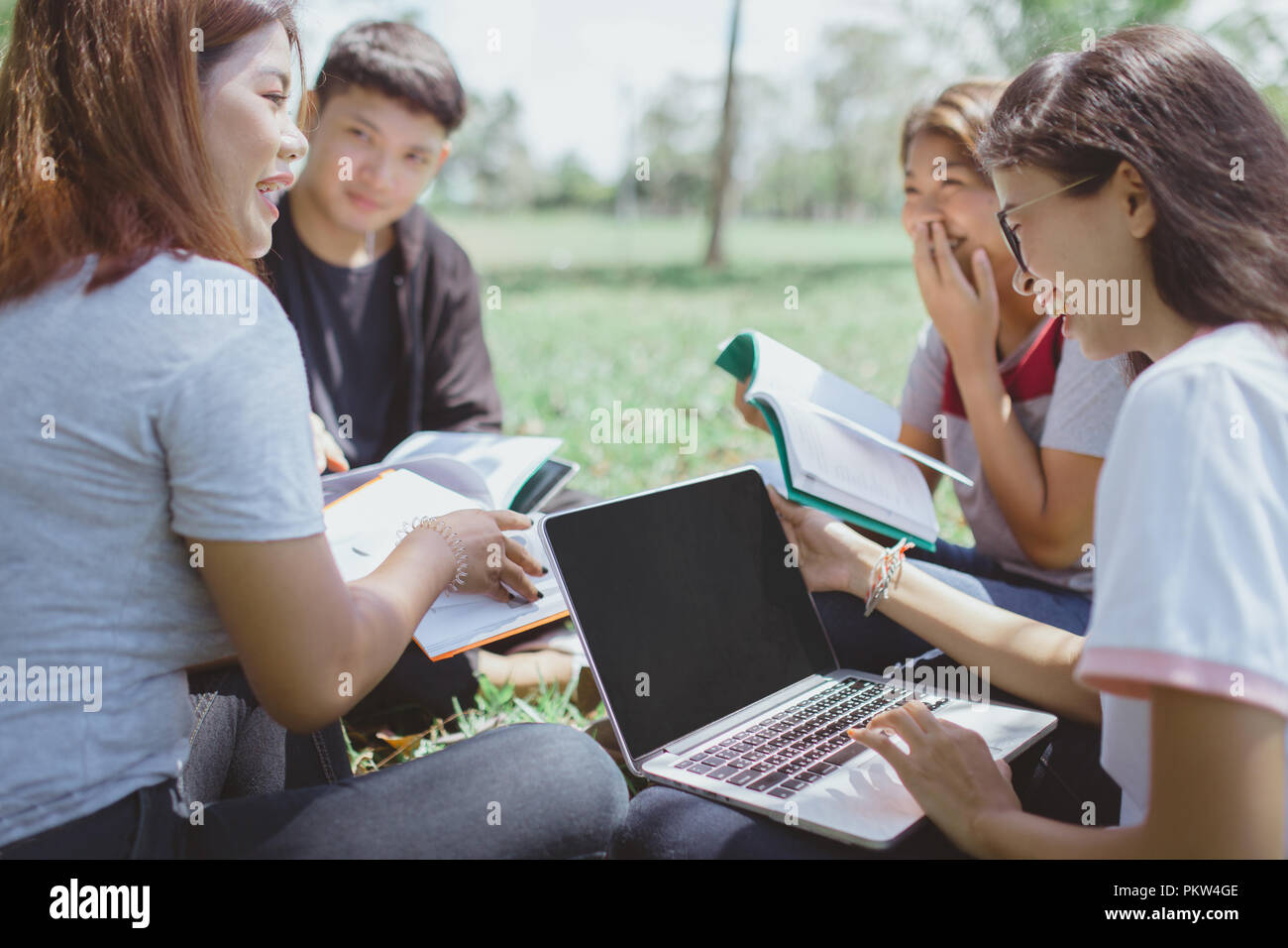 Group of student used computer and reading books on lawn. education and ...