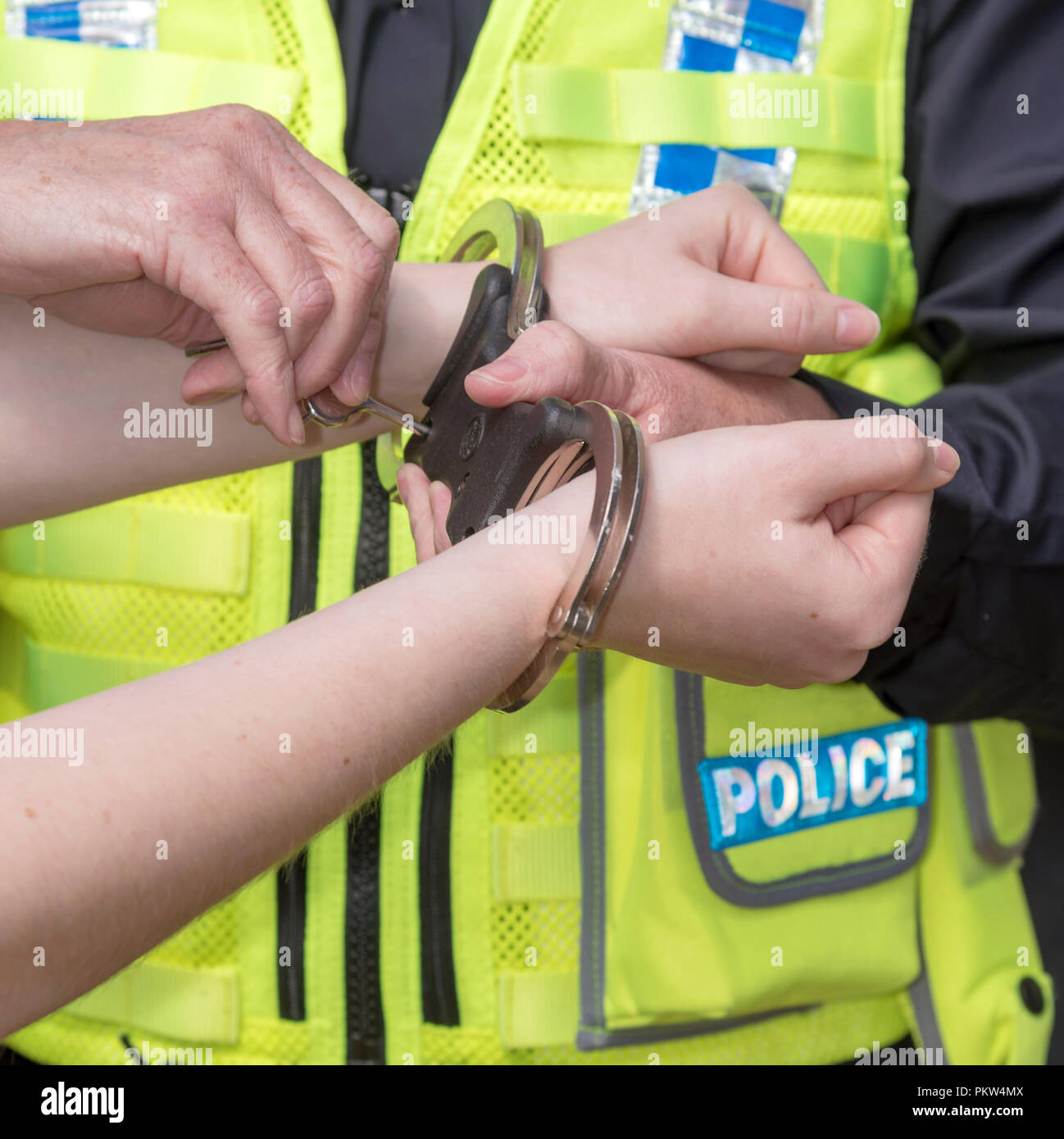 Police officer turning key of handcuffs Stock Photo - Alamy