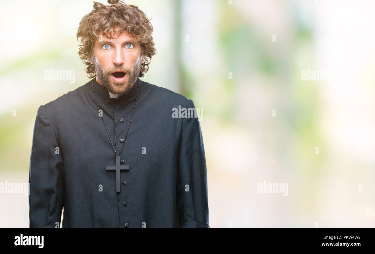 Handsome hispanic catholic priest man over isolated background afraid ...