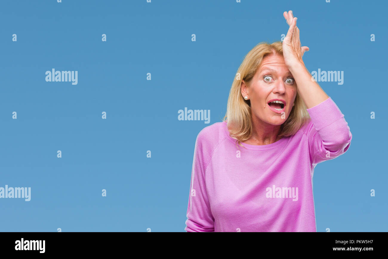 Middle age blonde woman over isolated background surprised with hand on ...
