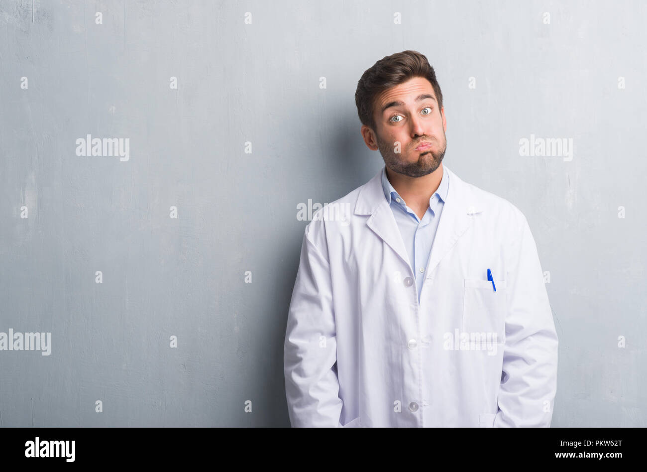 Handsome young professional man over grey grunge wall wearing white ...