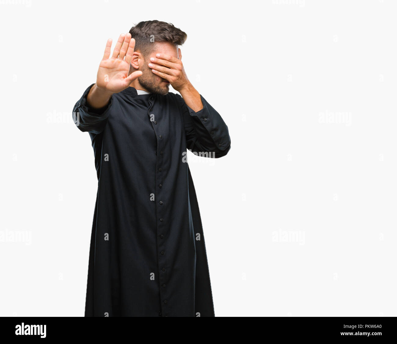Young catholic christian priest man over isolated background covering ...