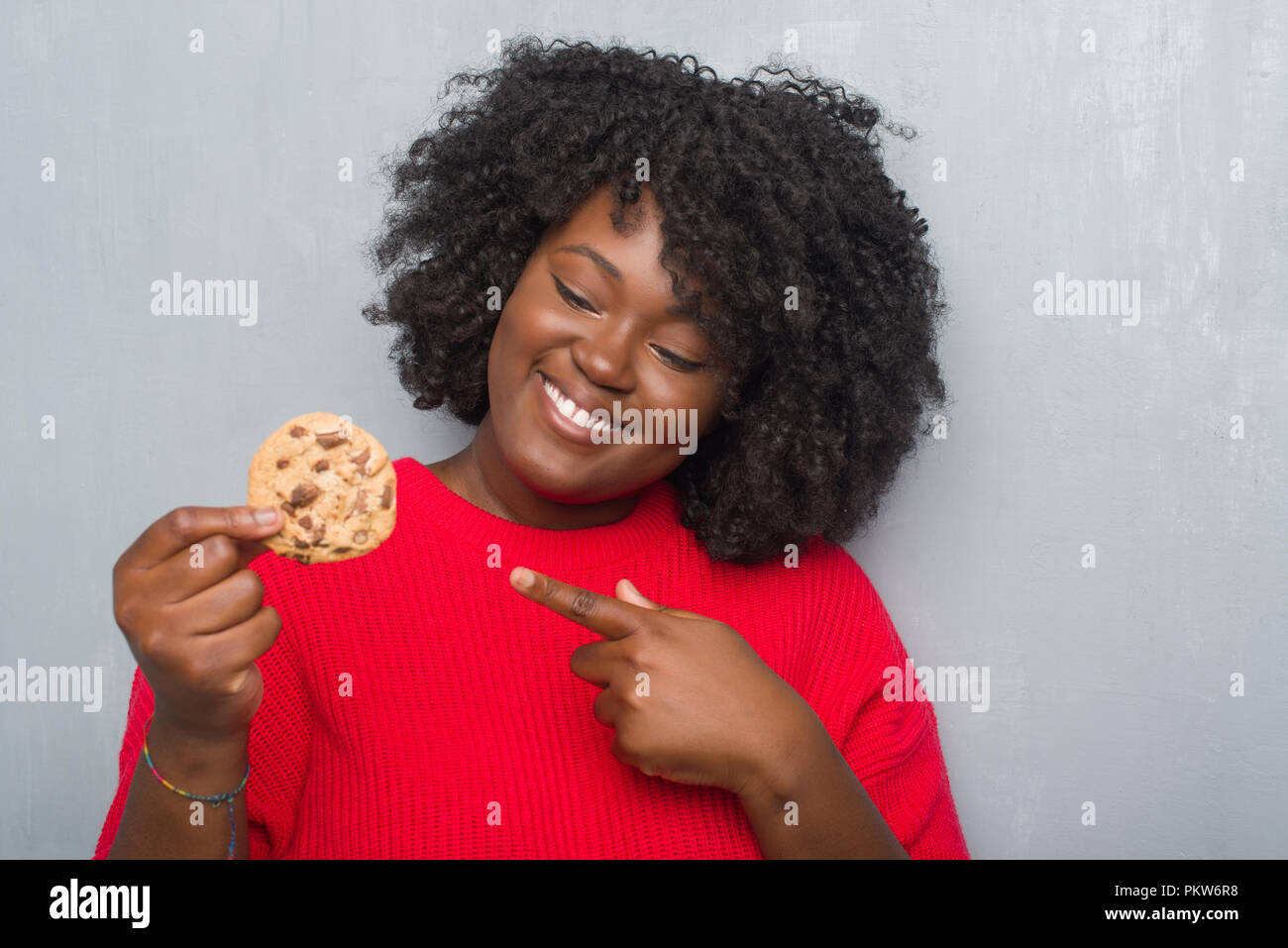 Young african american woman over grey grunge wall eating chocolate ...