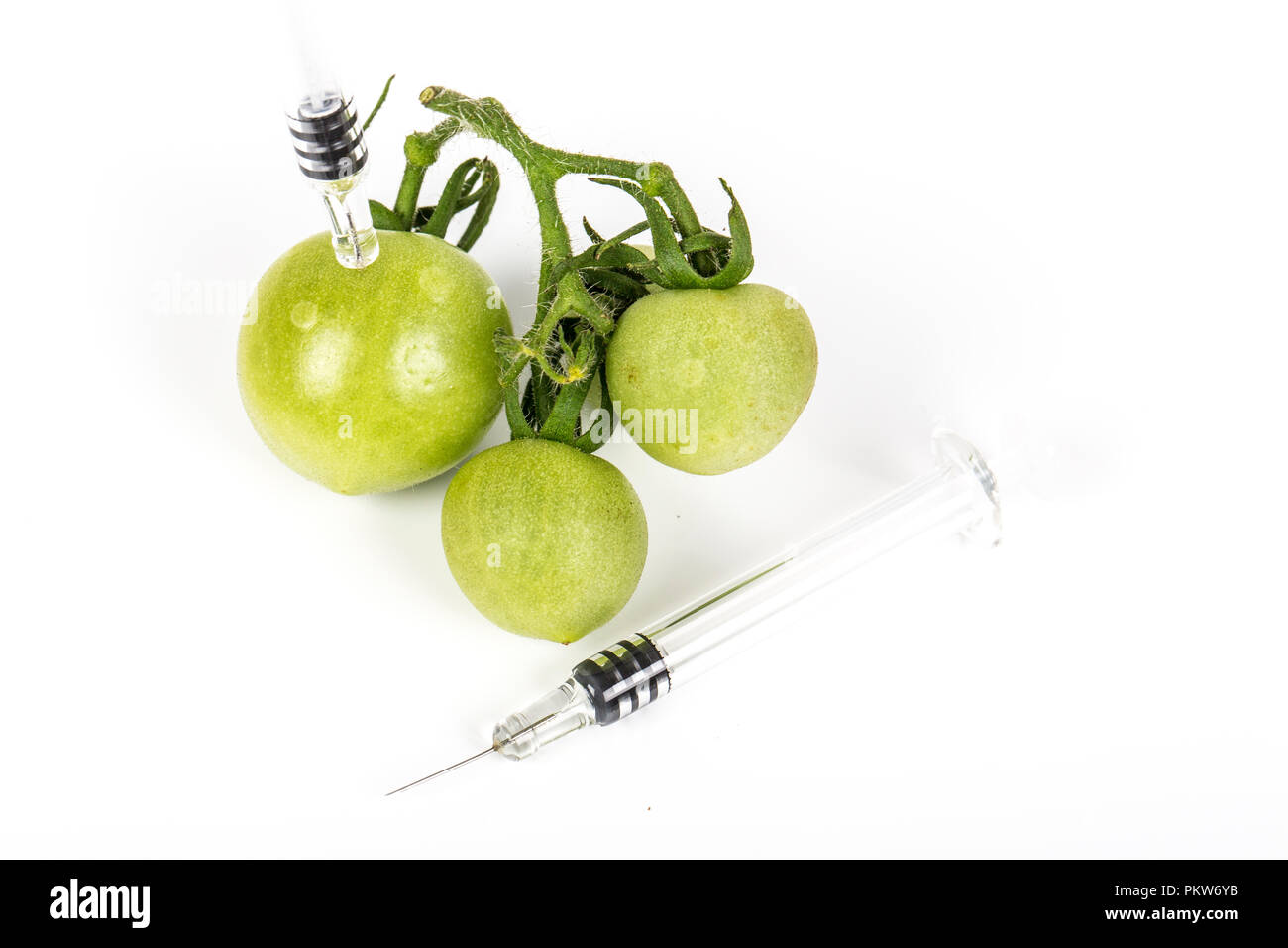 Small green tomatoes grape with syringe. Concept non organic food ...