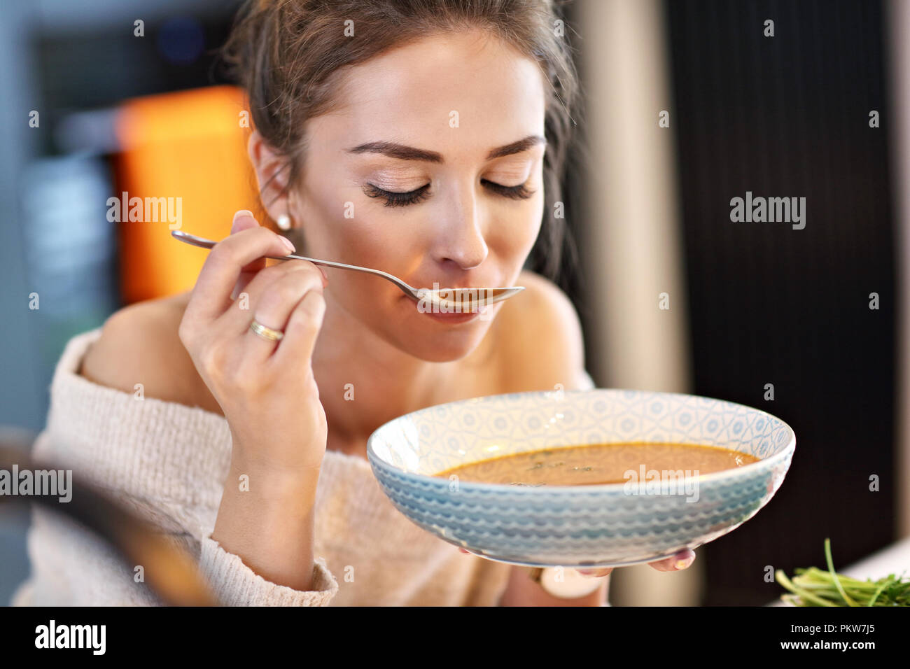 Adult woman eating pumpkin soup in the kitchen Stock Photo - Alamy